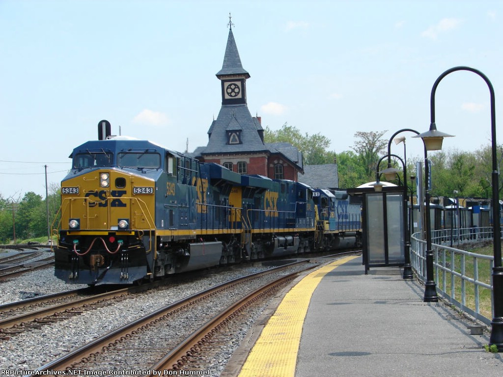 Big new power rolls past quaint old station.